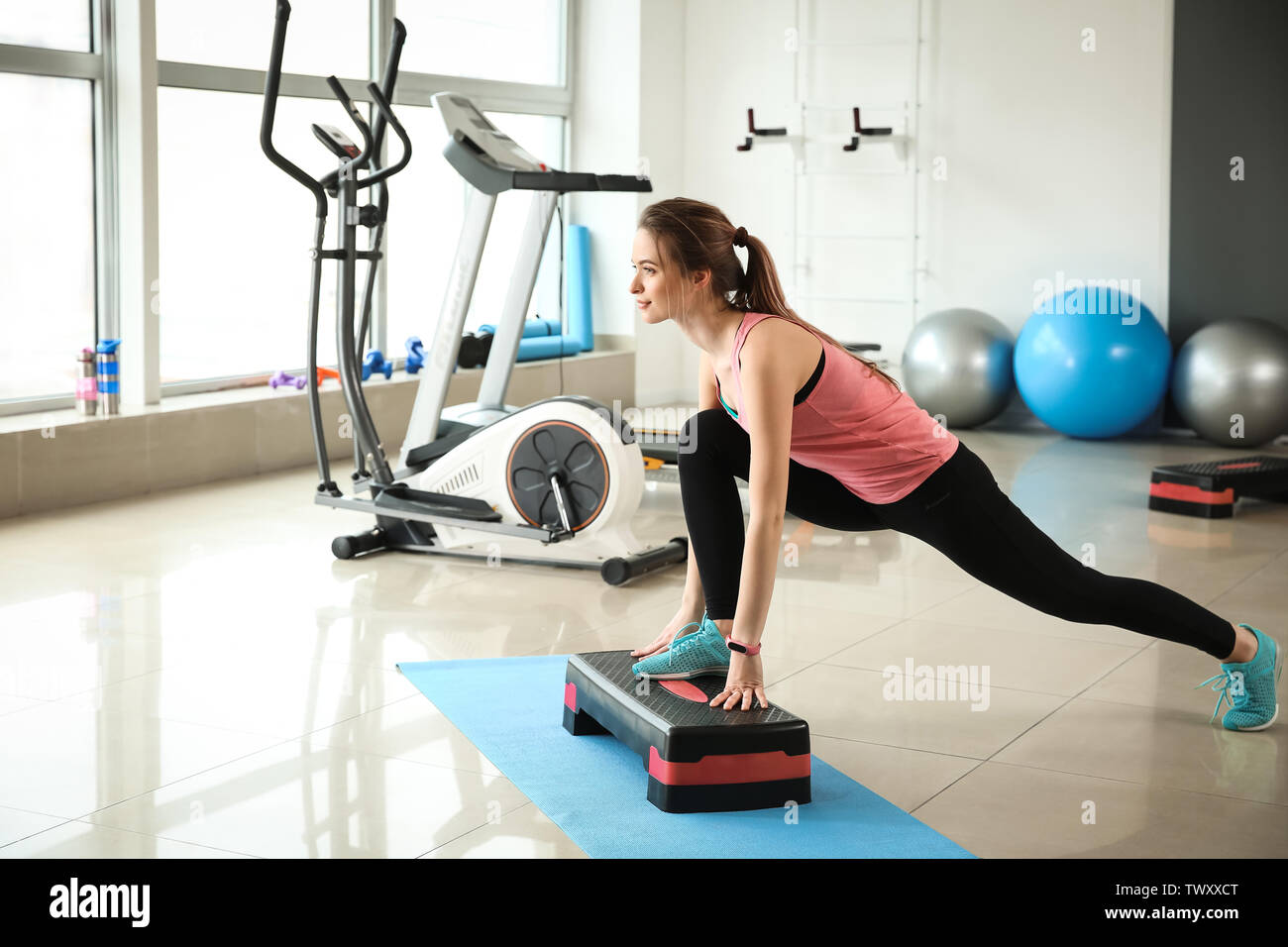 Sporty young woman training with stepper in gym Stock Photo - Alamy
