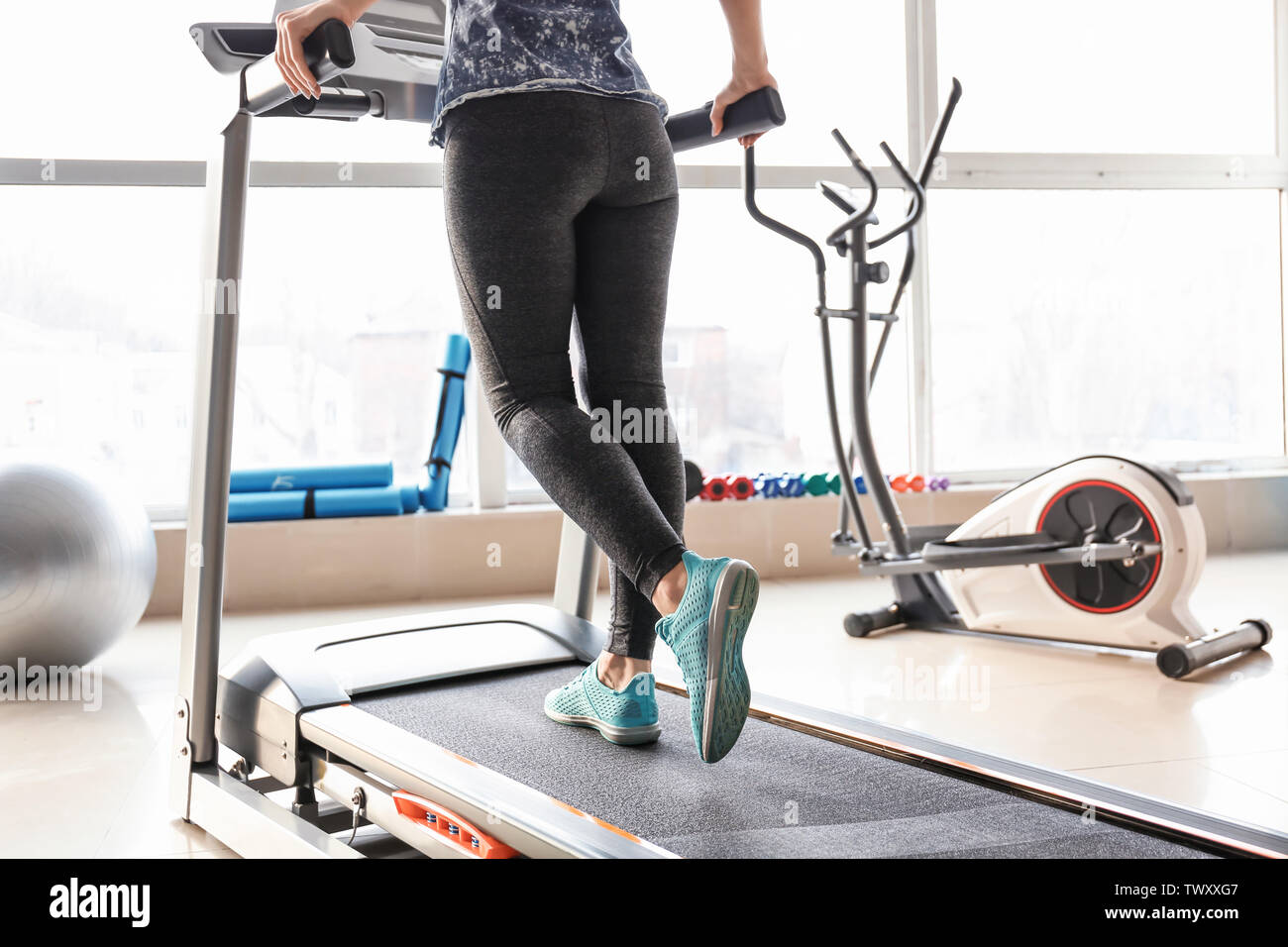 Sporty young woman training on machine in gym Stock Photo - Alamy