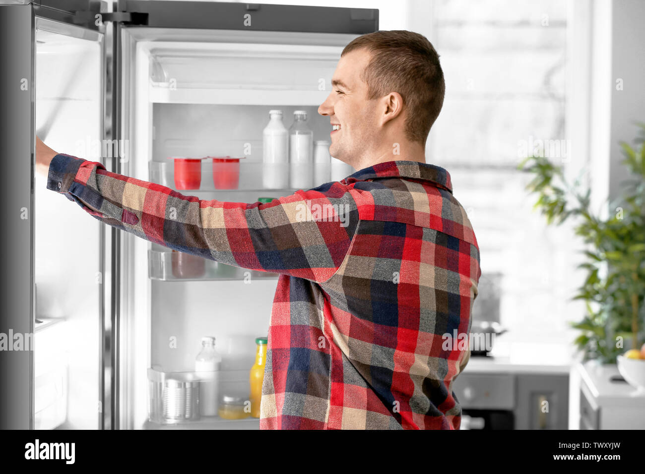 Man taking food out of fridge at home Stock Photo - Alamy