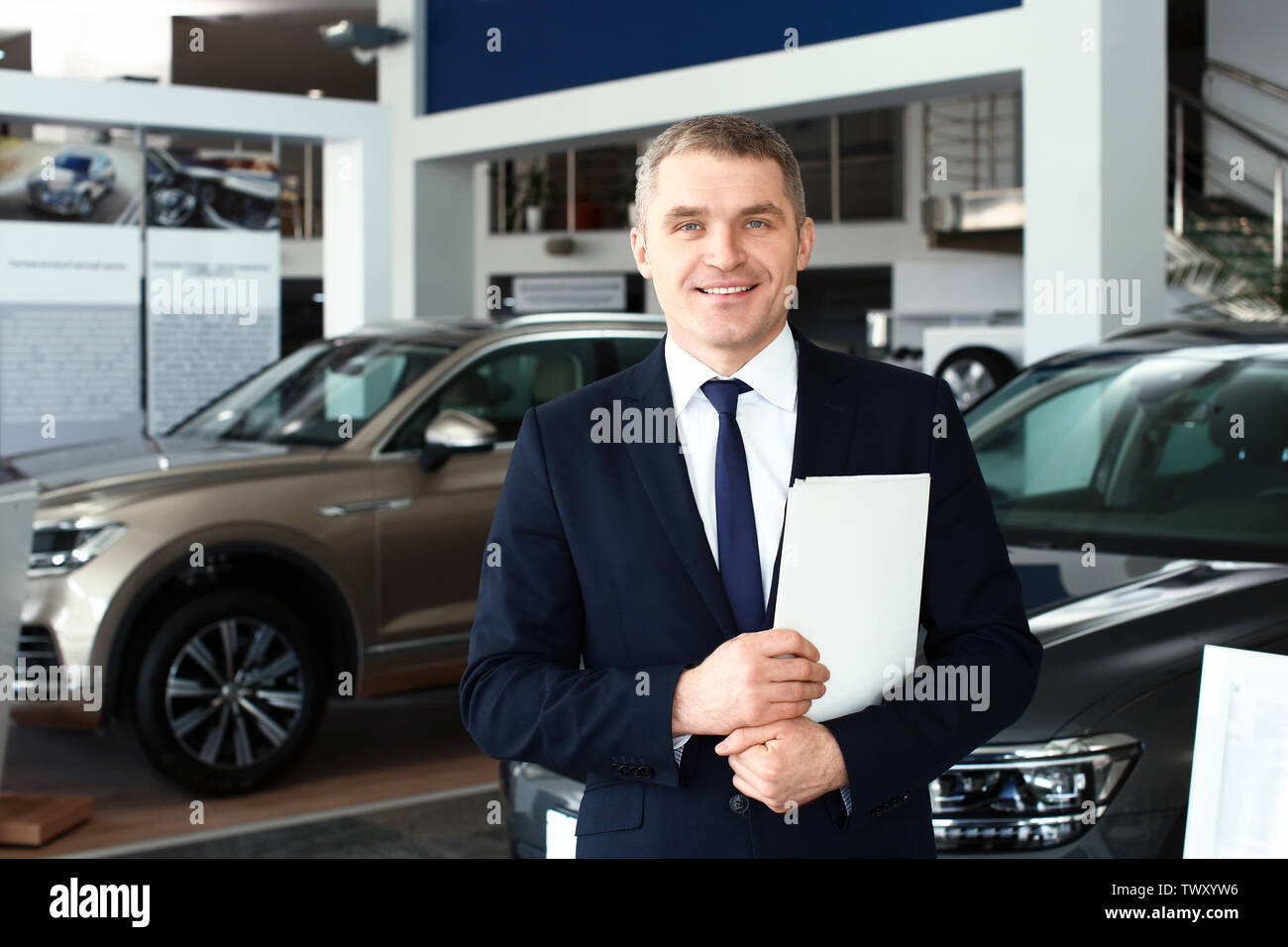 Salesman in modern car showroom Stock Photo - Alamy