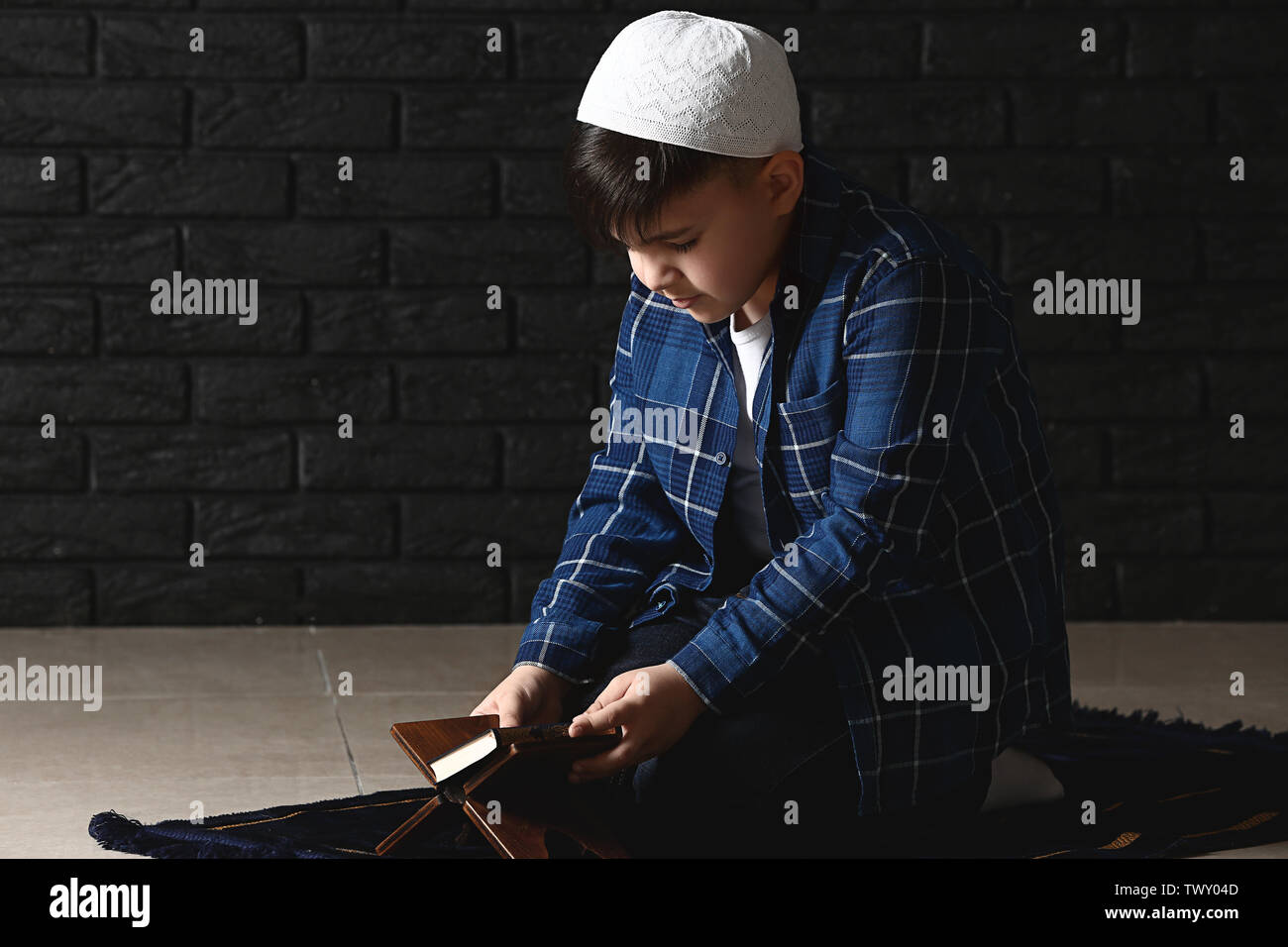 Little Muslim boy praying against dark wall Stock Photo - Alamy