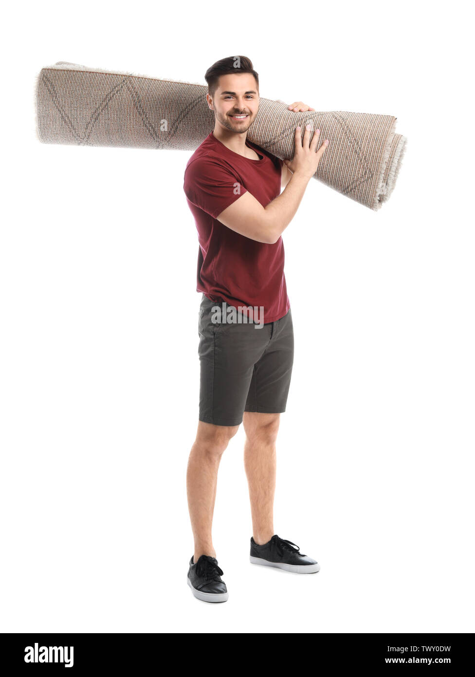 Young man holding rolled carpet against white background Stock Photo ...