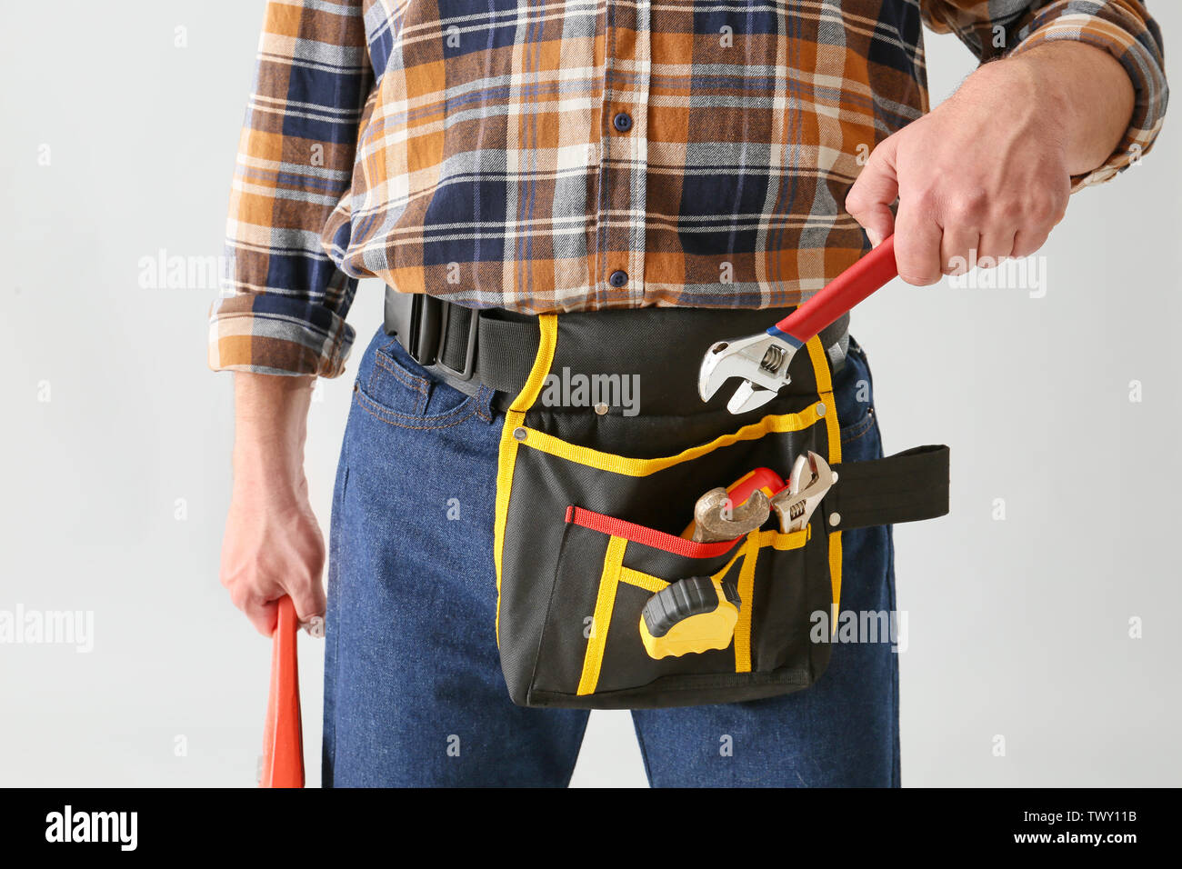 Plumber with tools belt on light background, closeup Stock Photo - Alamy