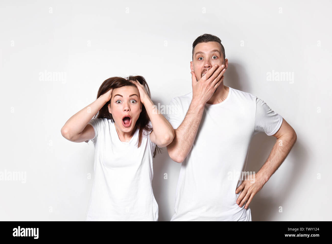 Shocked young couple on light background Stock Photo - Alamy