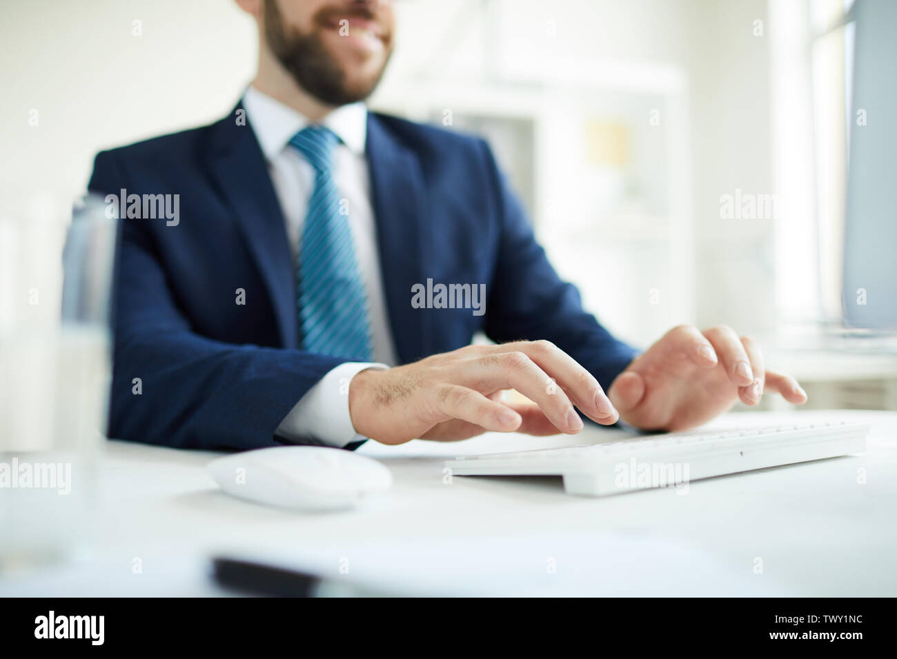 Close-up of busy male manager sitting at desk and typing on computer ...