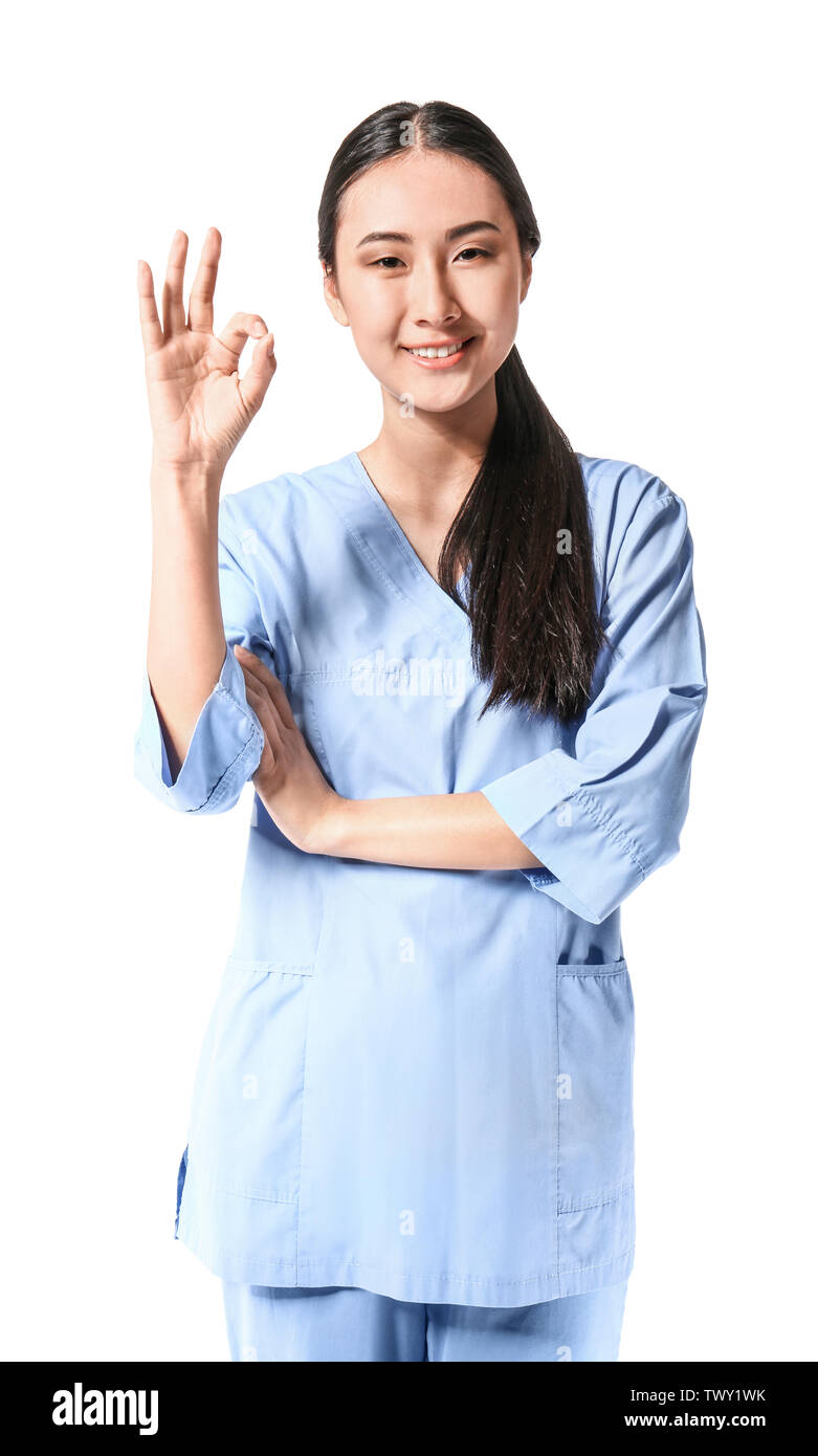 Portrait of young Asian physiotherapist showing OK gesture on white ...