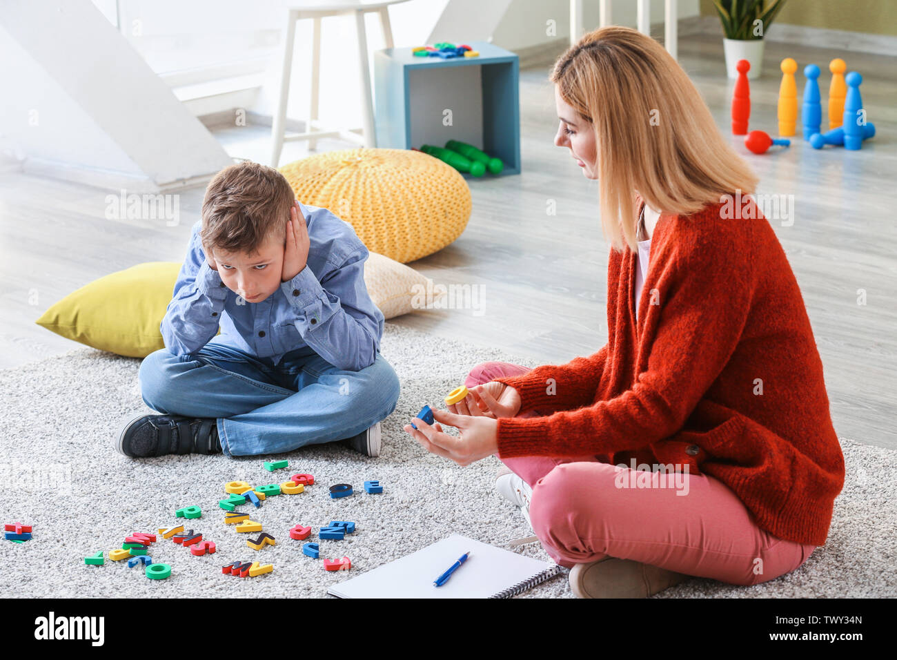 Female psychologist working with boy suffering from autistic disorder ...