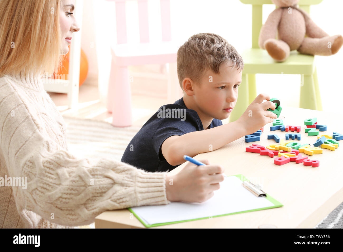 Female psychologist working with boy suffering from autistic disorder ...