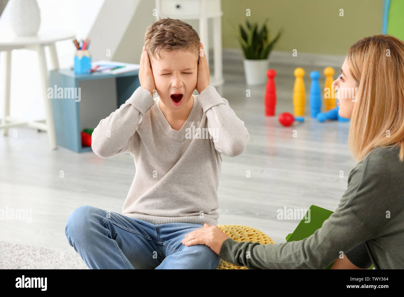 Female psychologist working with boy suffering from autistic disorder ...