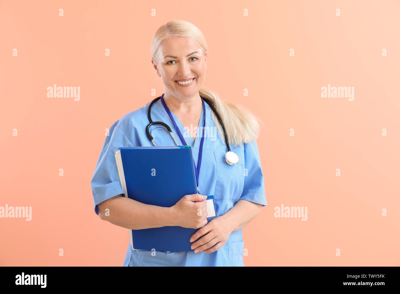Mature medical assistant on color background Stock Photo - Alamy