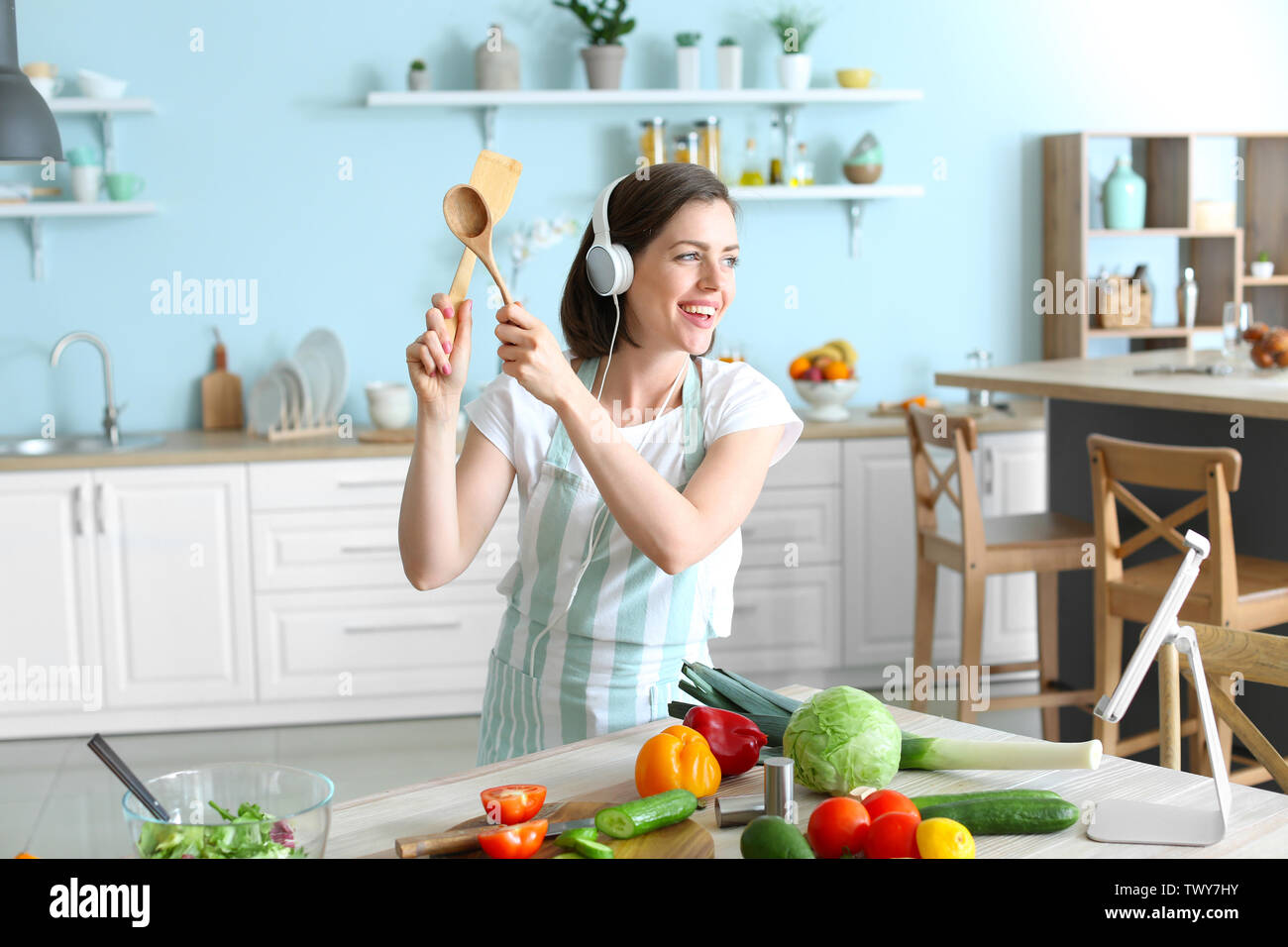 Beautiful young woman listening to music while cooking in kitchen Stock ...