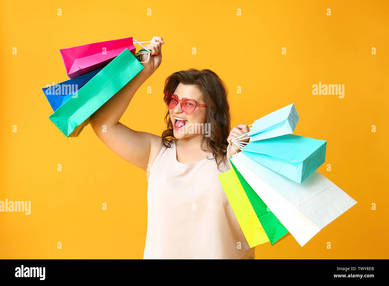Happy plus size woman with shopping bags on color background Stock ...