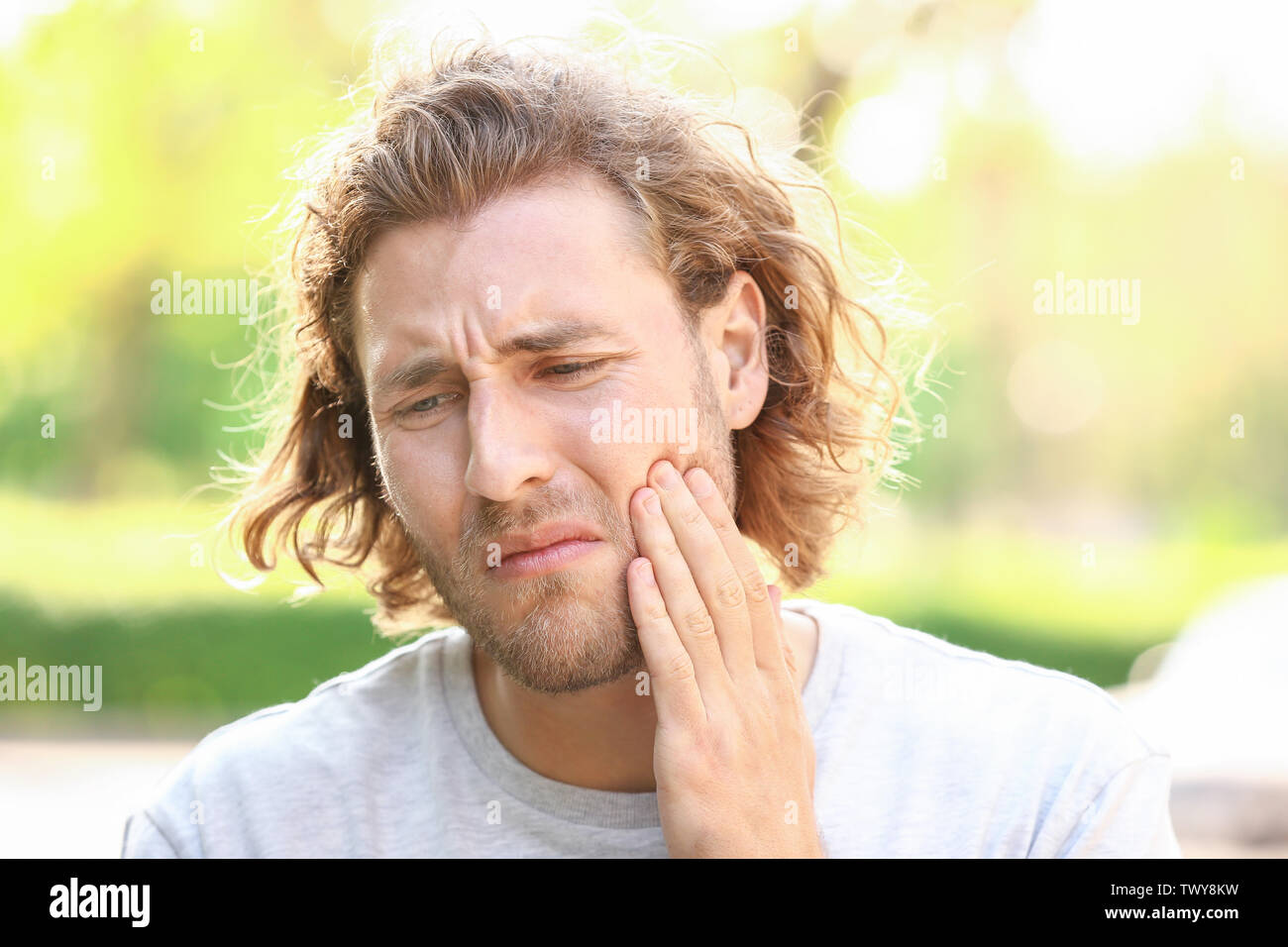 Young man suffering from toothache outdoors Stock Photo - Alamy