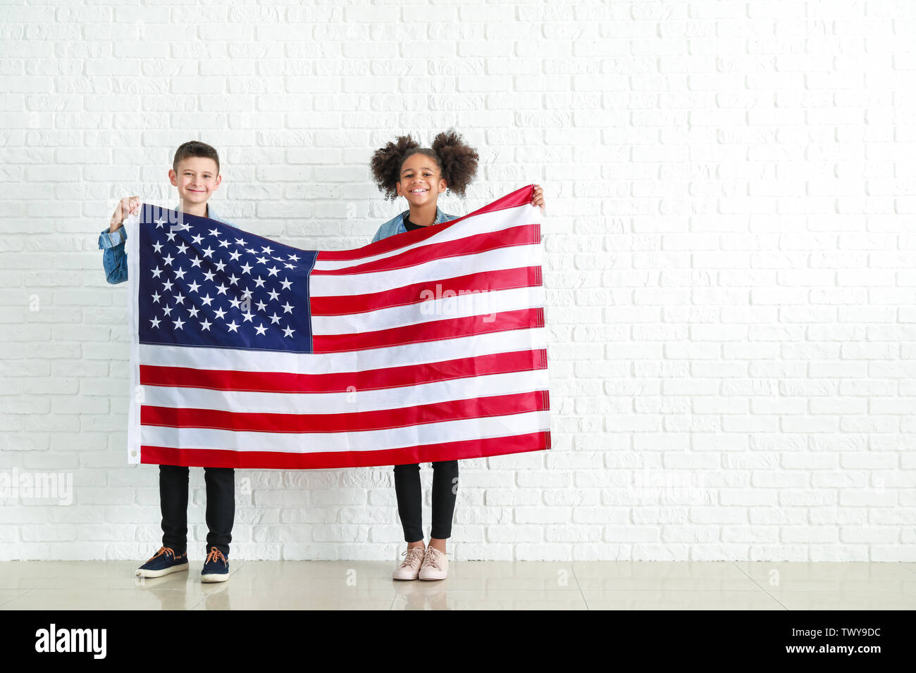 Cute children with national flag of USA near white brick wall Stock ...