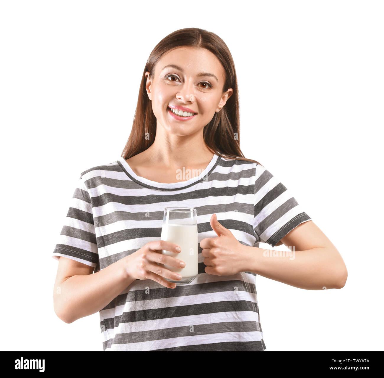Beautiful woman with glass of tasty milk showing thumb-up gesture on ...