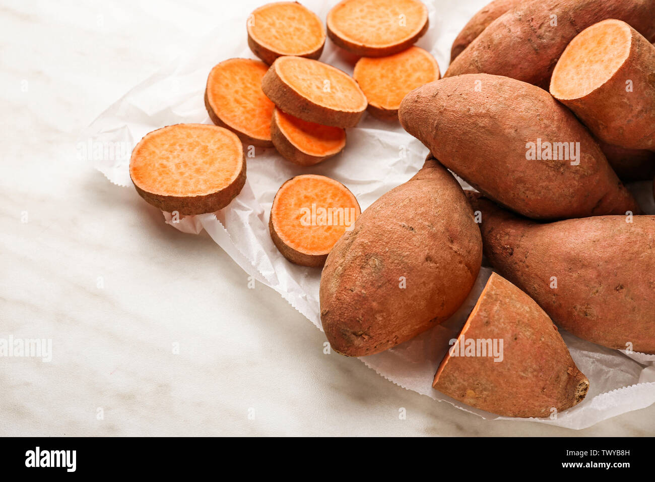 Raw sweet potato on light background Stock Photo - Alamy