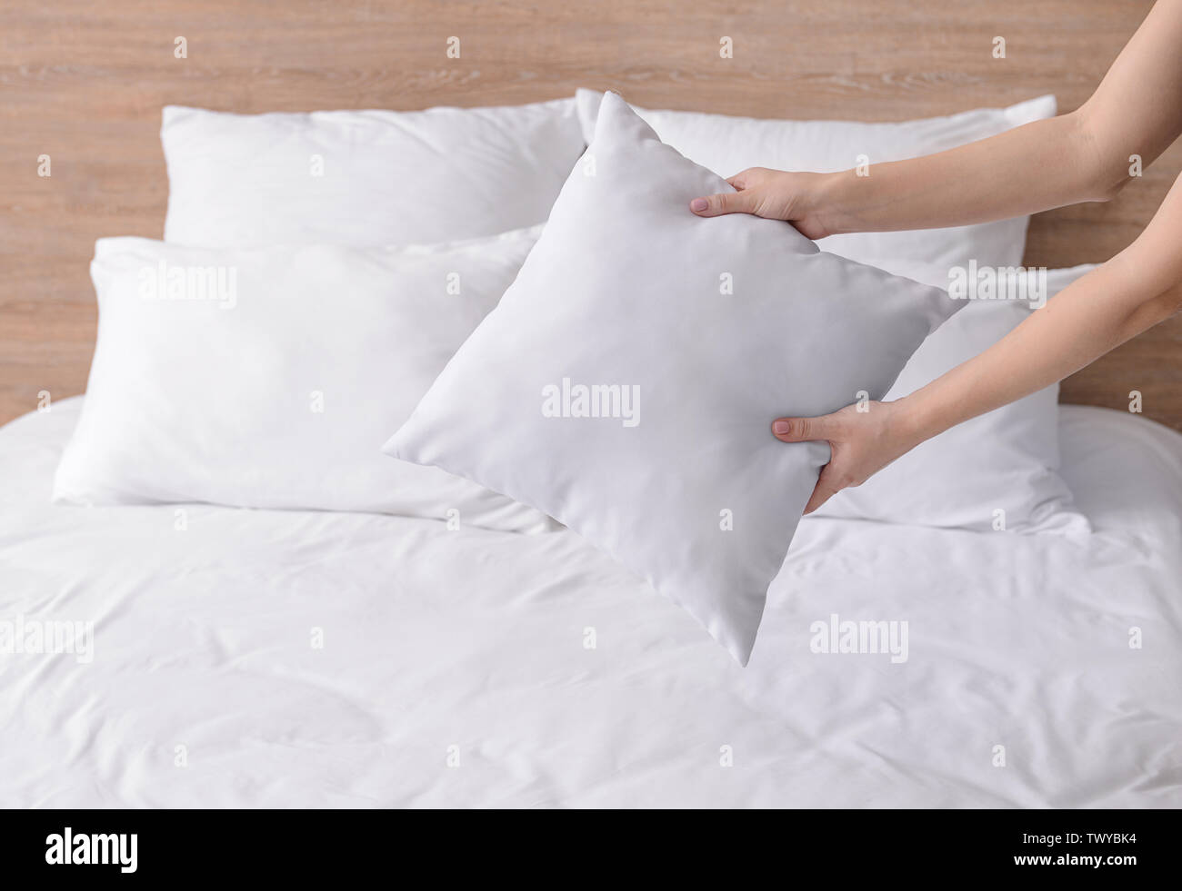 Woman fluffing soft pillows on bed Stock Photo - Alamy