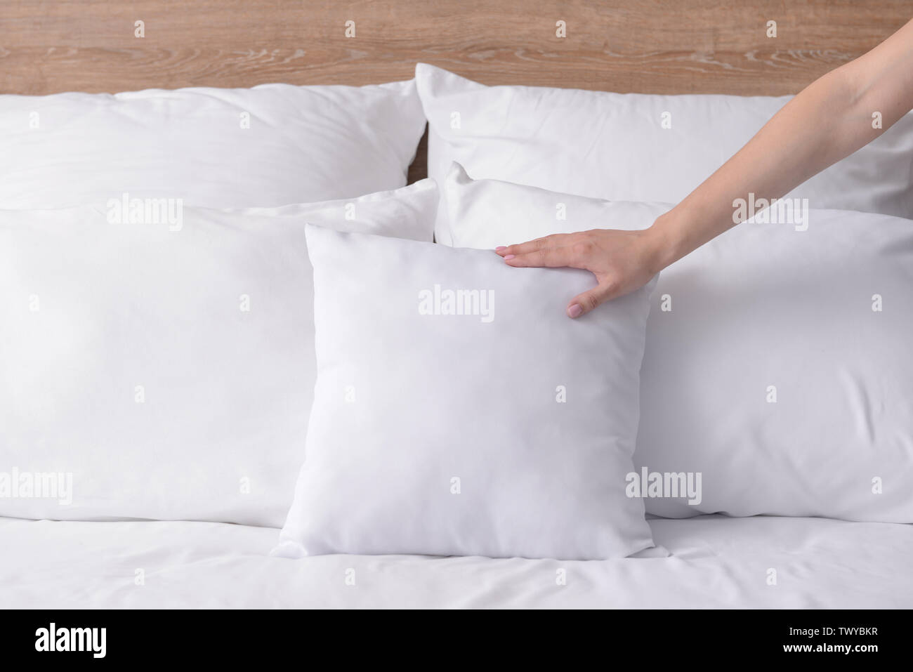 Woman fluffing soft pillows on bed Stock Photo - Alamy