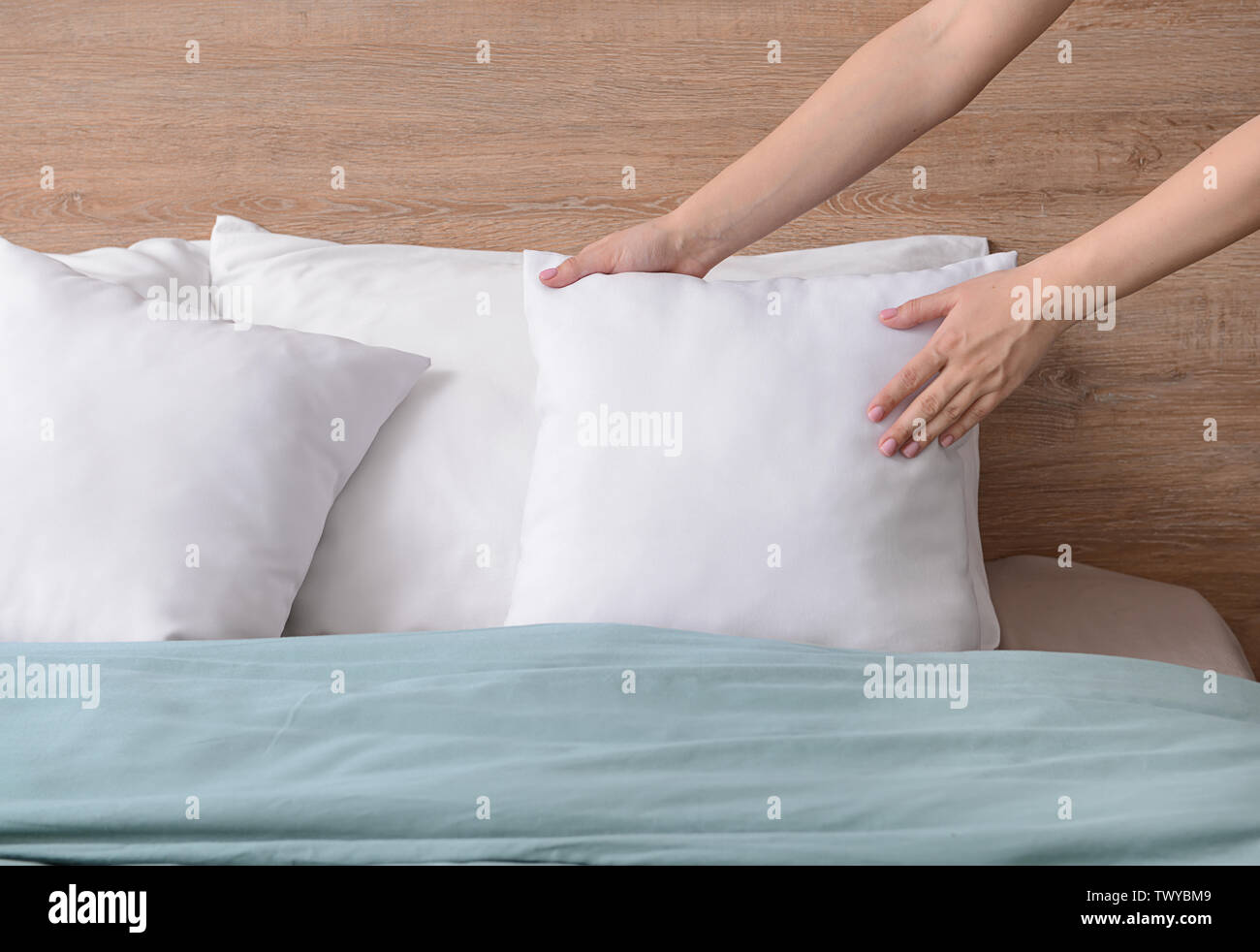 Woman fluffing soft pillows on bed Stock Photo - Alamy