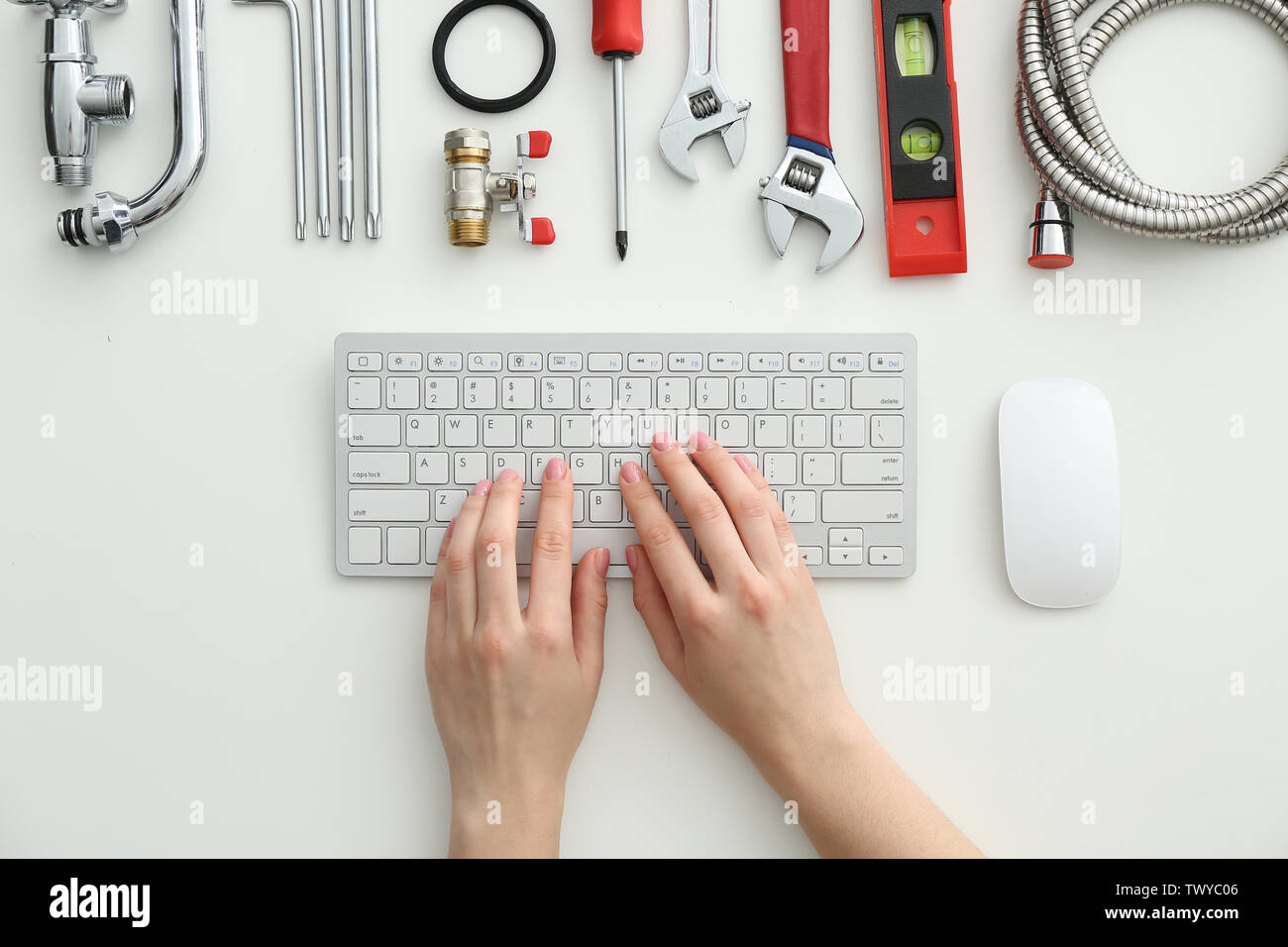 Plumbing tools and woman with computer keyboard on white background ...