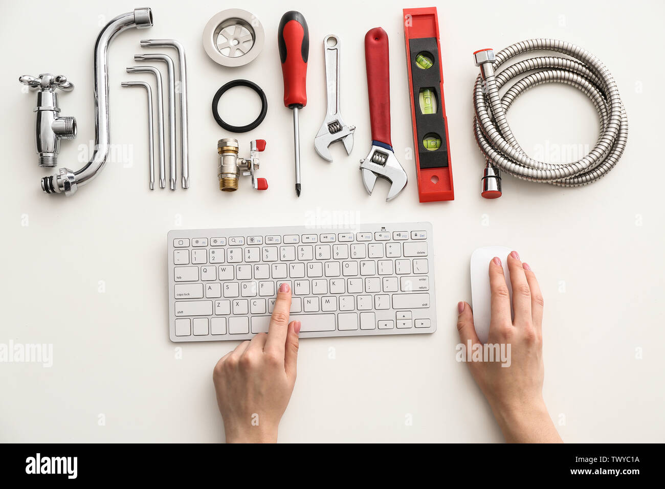 Plumbing tools and woman with computer keyboard on white background ...