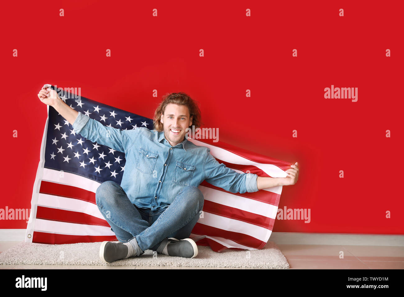Happy young man with USA flag near color wall. Independence Day ...