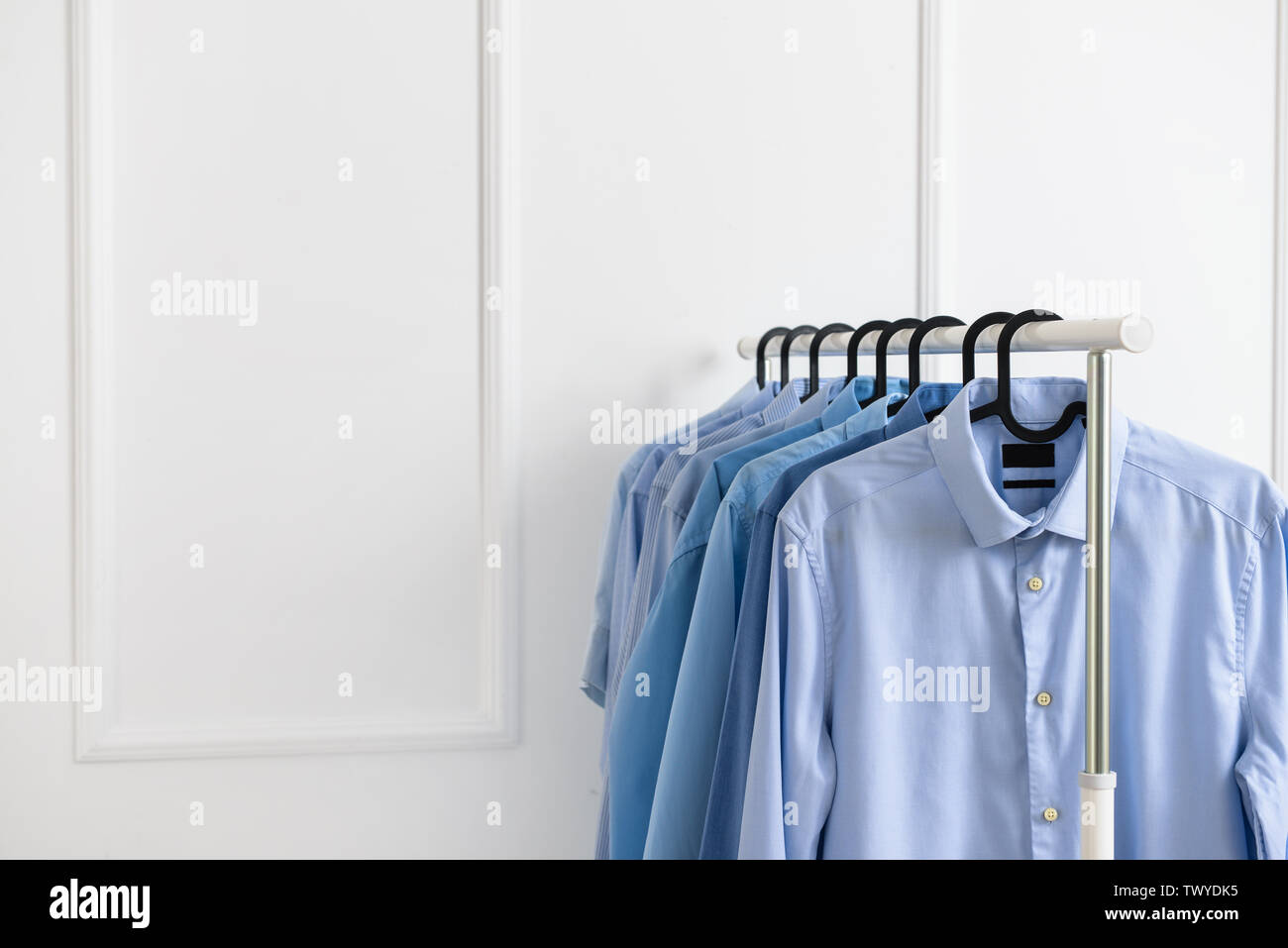 Rack with clothes after dry-cleaning near white wall Stock Photo - Alamy