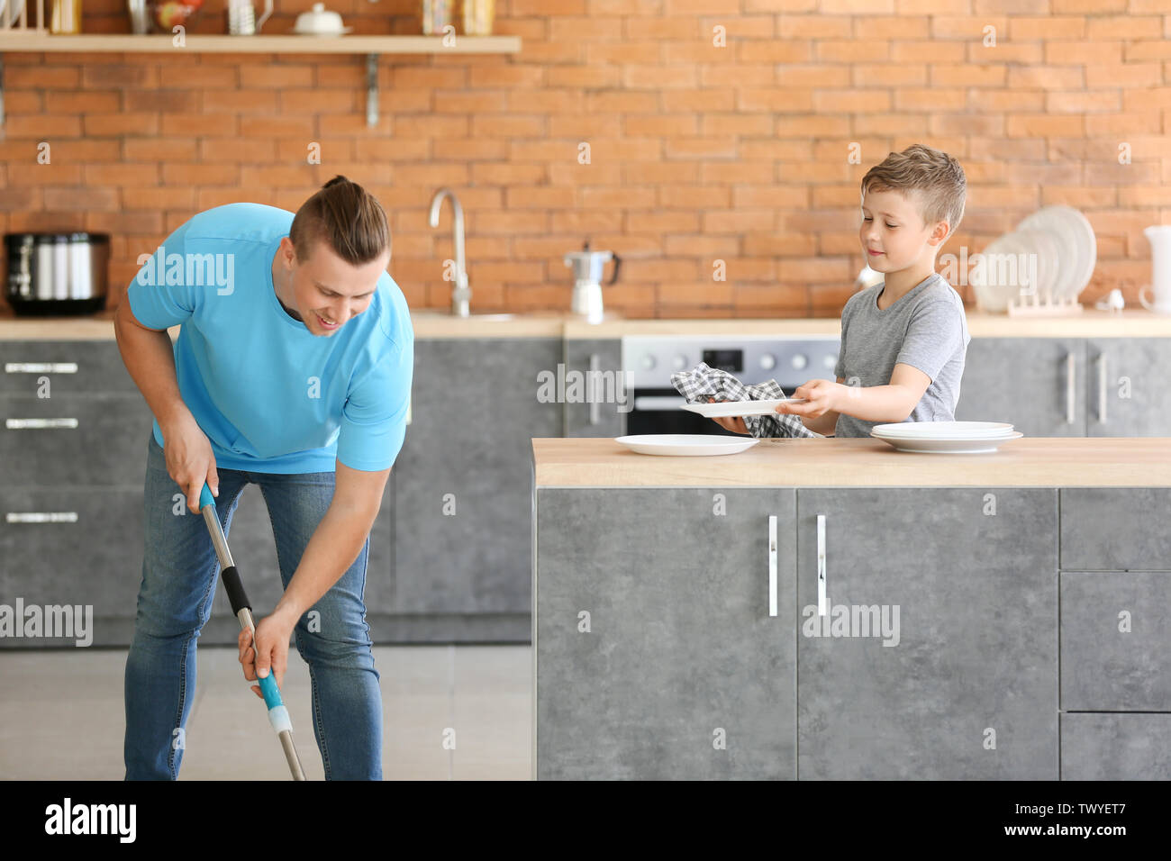 Father and son cleaning kitchen together Stock Photo - Alamy