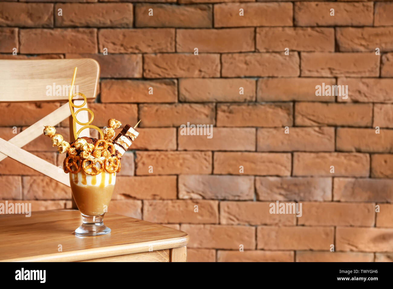 Delicious freak shake on wooden chair against brick background Stock ...