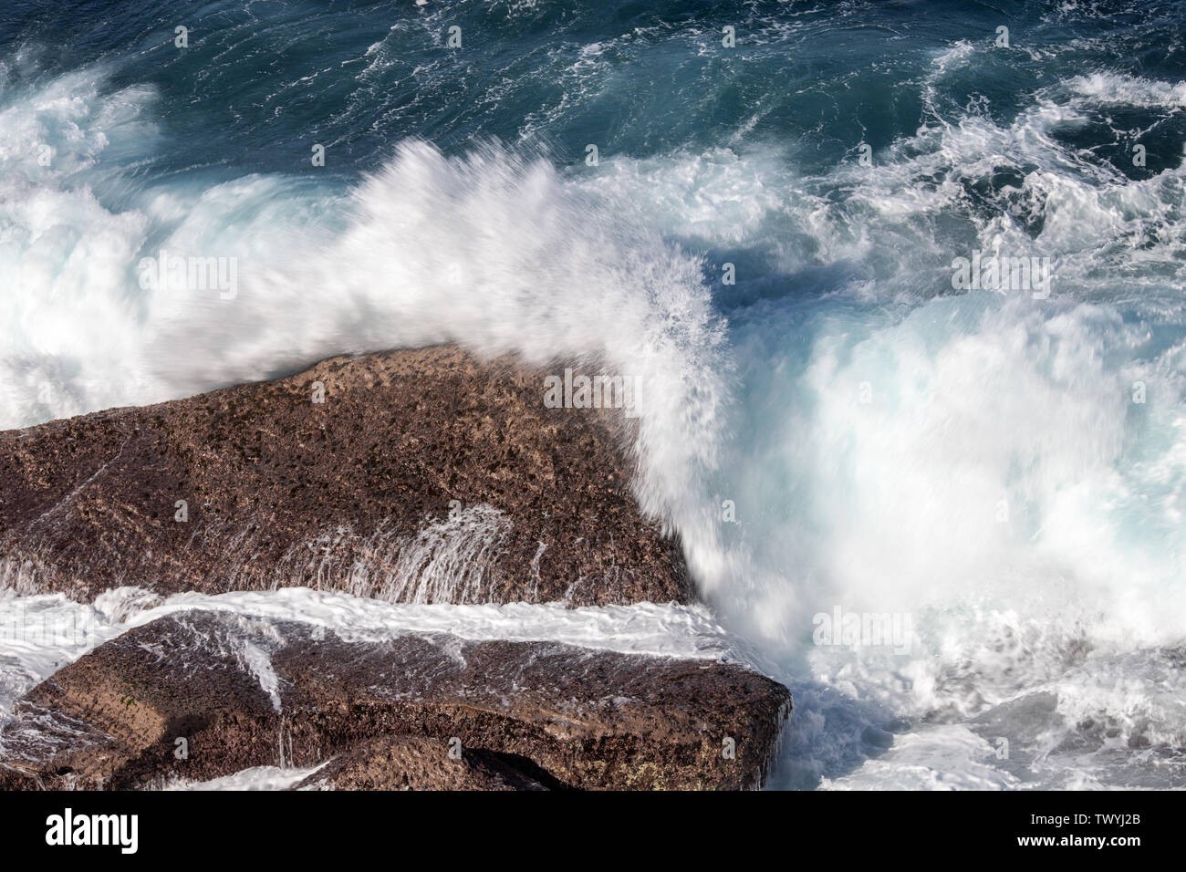 Wave breaking onto rocks Stock Photo - Alamy