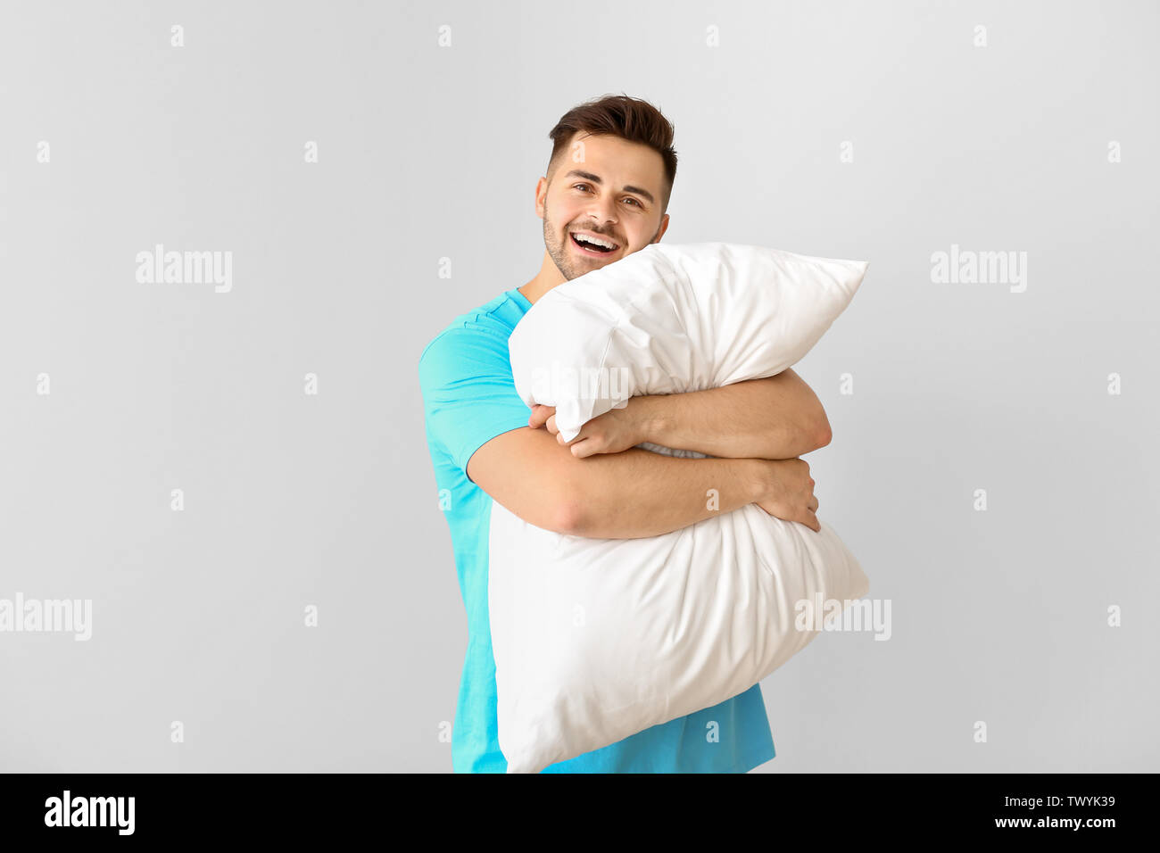 Handsome man hugging pillow against white background Stock Photo - Alamy