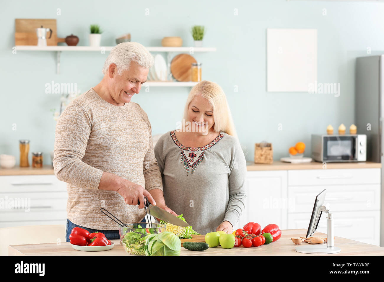 Portrait of happy mature couple cooking in kitchen Stock Photo - Alamy