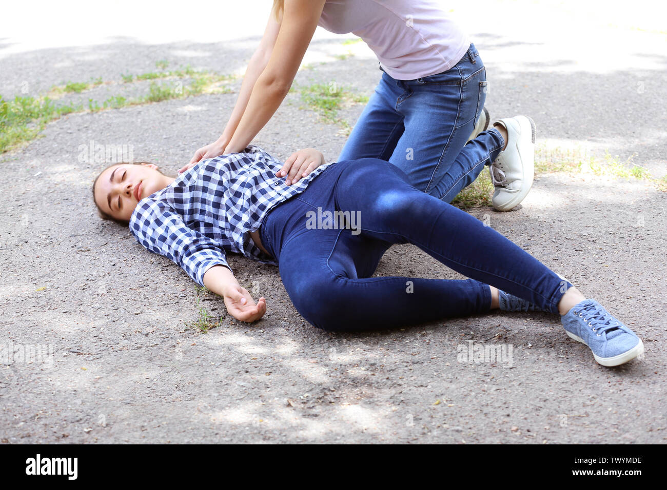 Female passer-by doing CPR on unconscious woman outdoors Stock Photo ...