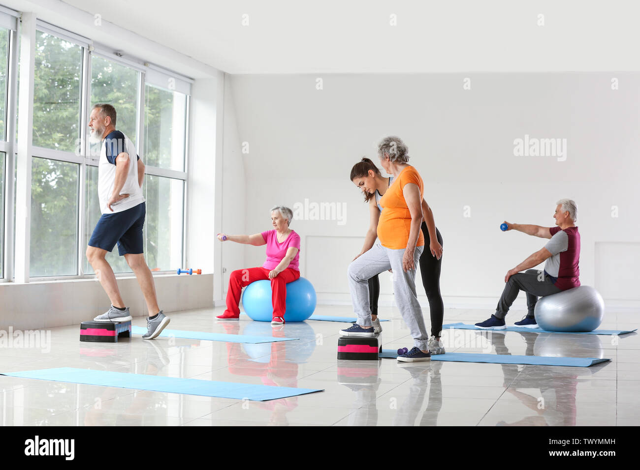 Elderly people training with instructor in gym Stock Photo - Alamy