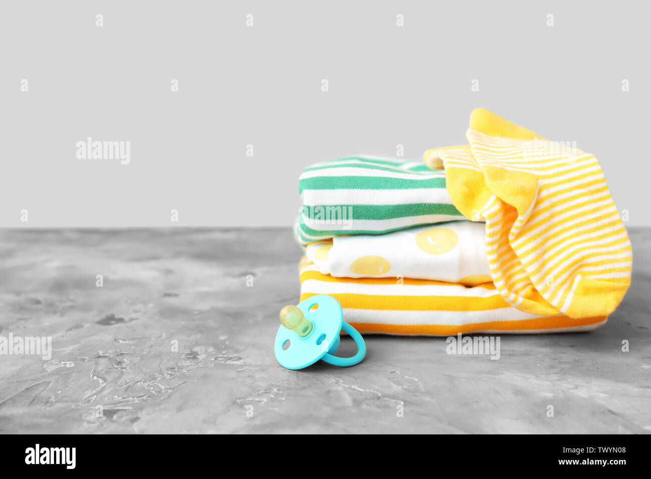 Stack of baby clothes and pacifier on table Stock Photo - Alamy