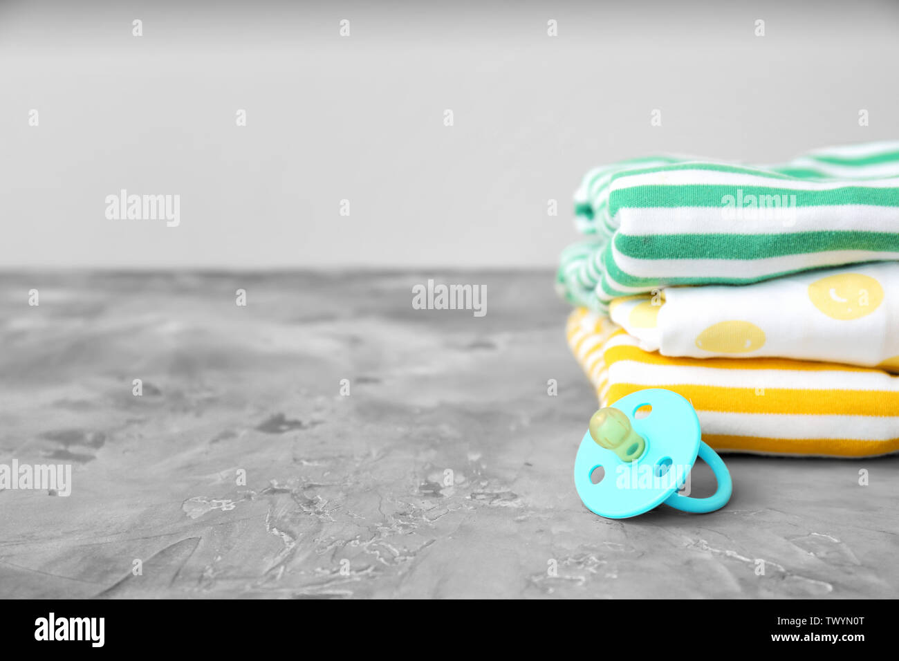 Stack of baby clothes and pacifier on table Stock Photo - Alamy