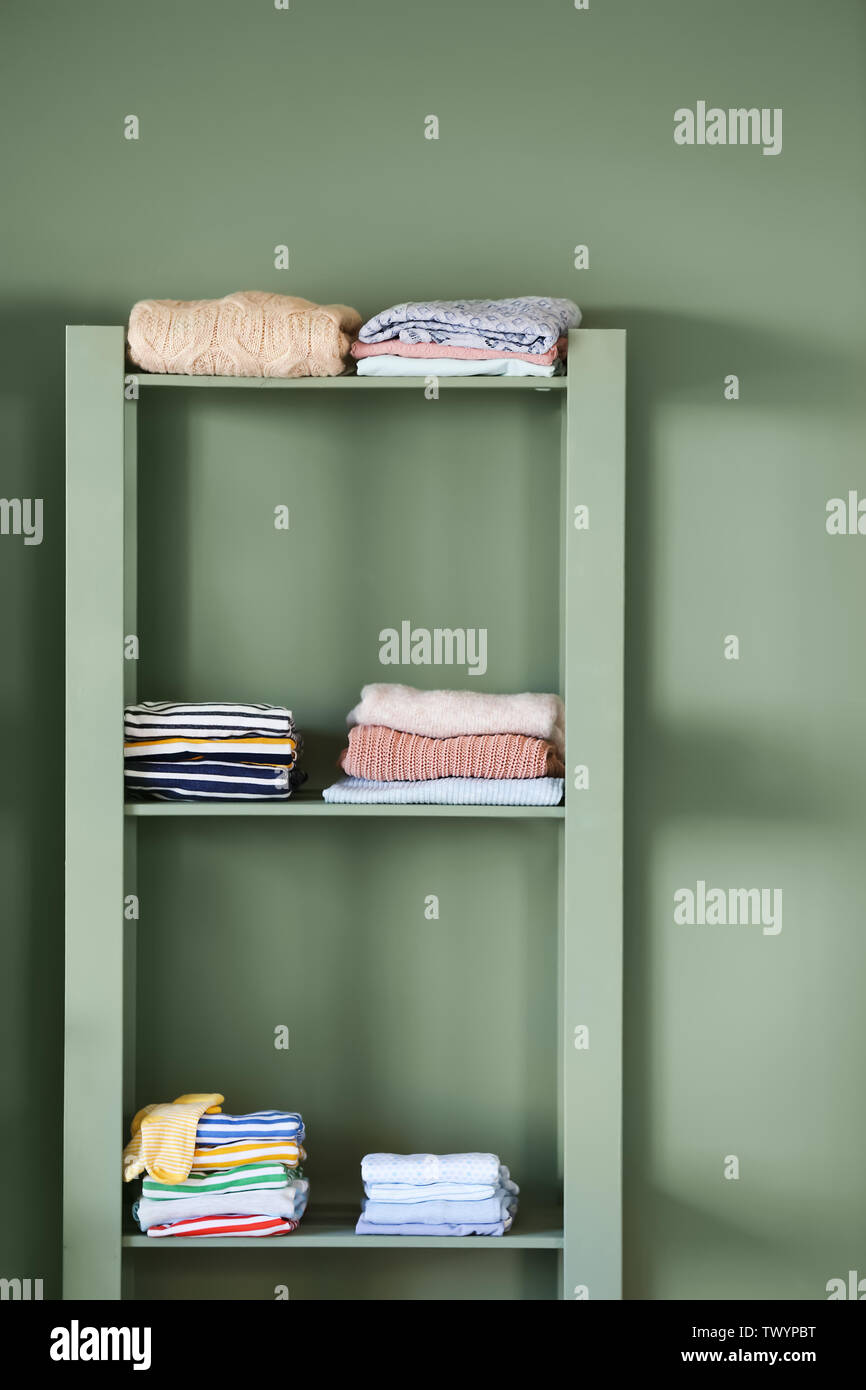 Rack with stacks of clean clothes on color background Stock Photo - Alamy