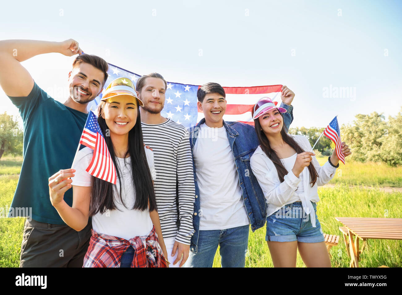 Young people with USA flags outdoors. Independence Day celebration ...
