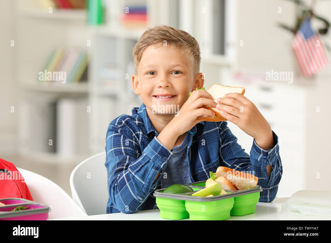 Little schoolboy eating tasty lunch in classroom Stock Photo - Alamy