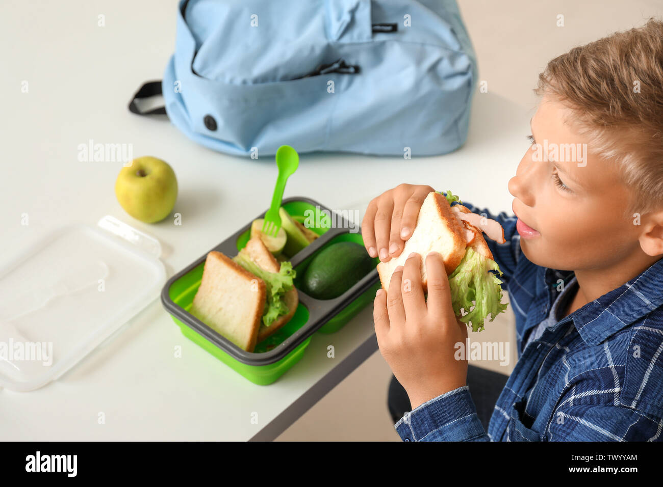 Little schoolboy eating tasty lunch in classroom Stock Photo - Alamy