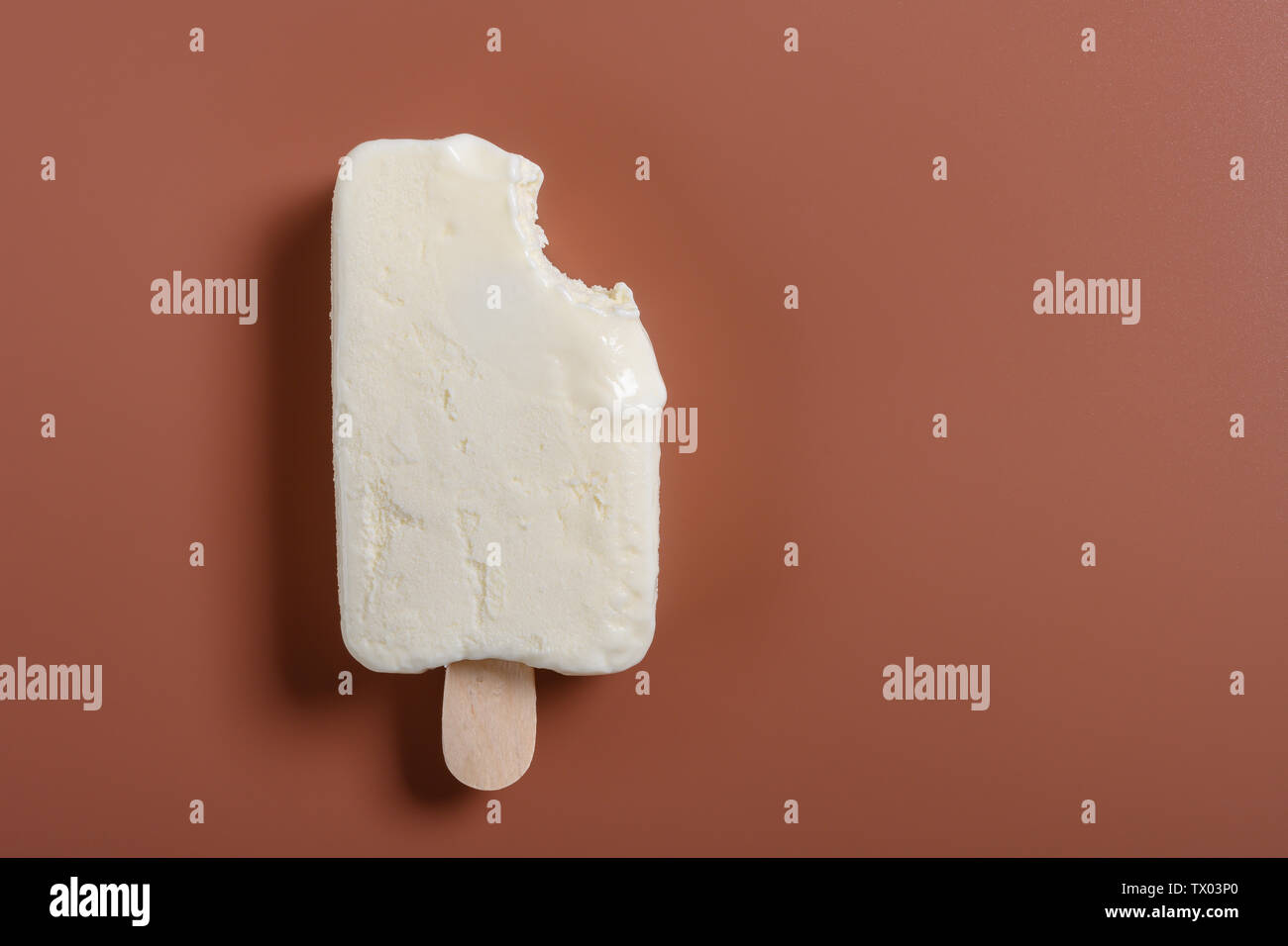 top view milkshake flavor popsicle with a bite on a brown background ...