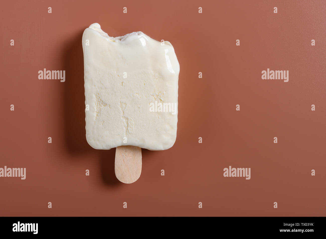top view half eaten milkshake flavor popsicle on a brown background ...