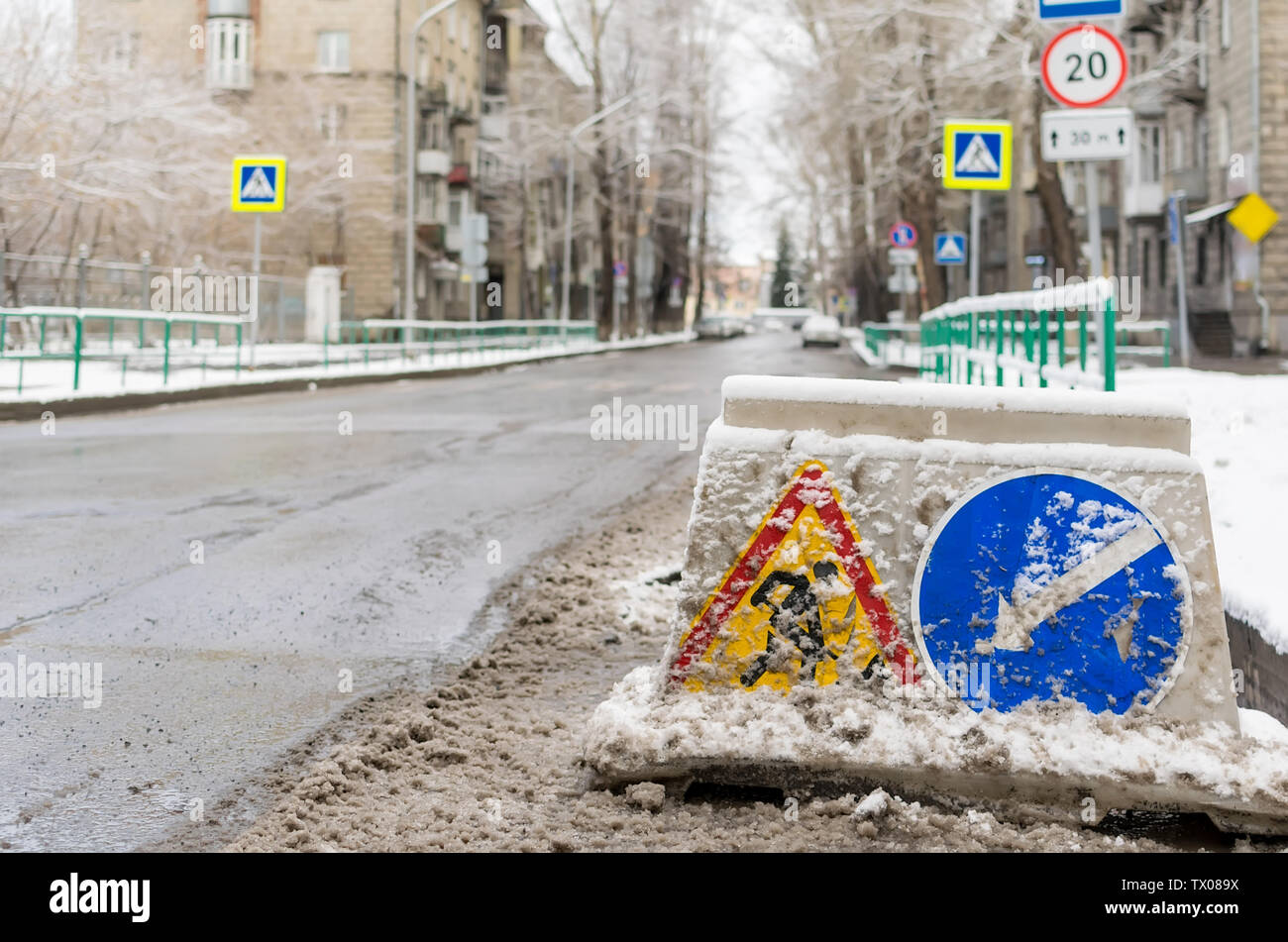 snow-swept road sign, road repair, stands on the roadway of the city ...