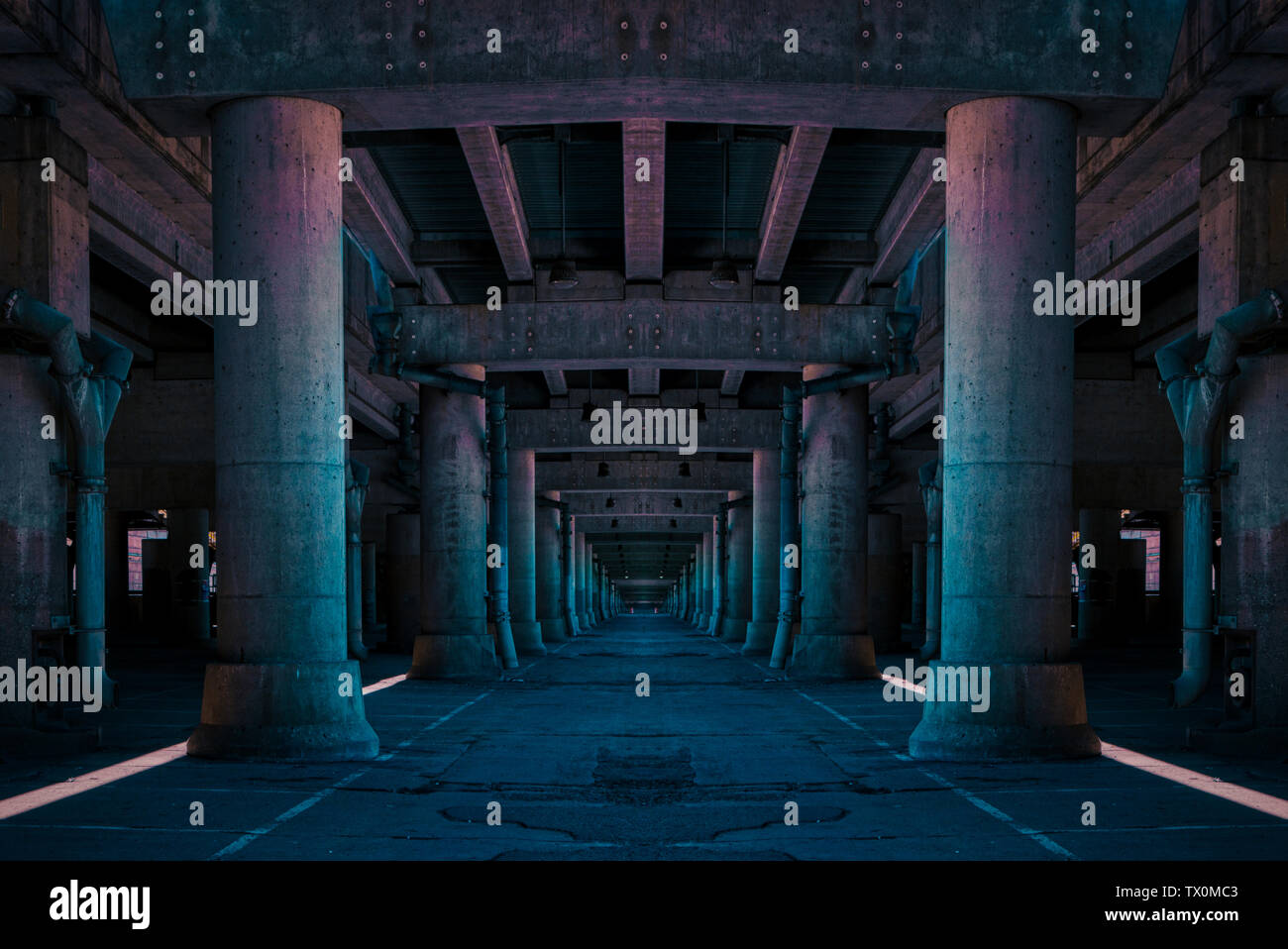 A long passageway with tall, thick columns with an eerie pink and blue ...