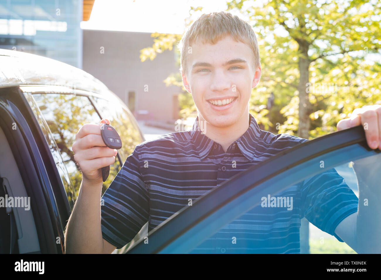 Happy teenager showing off his car keys as he stands next to his car ...