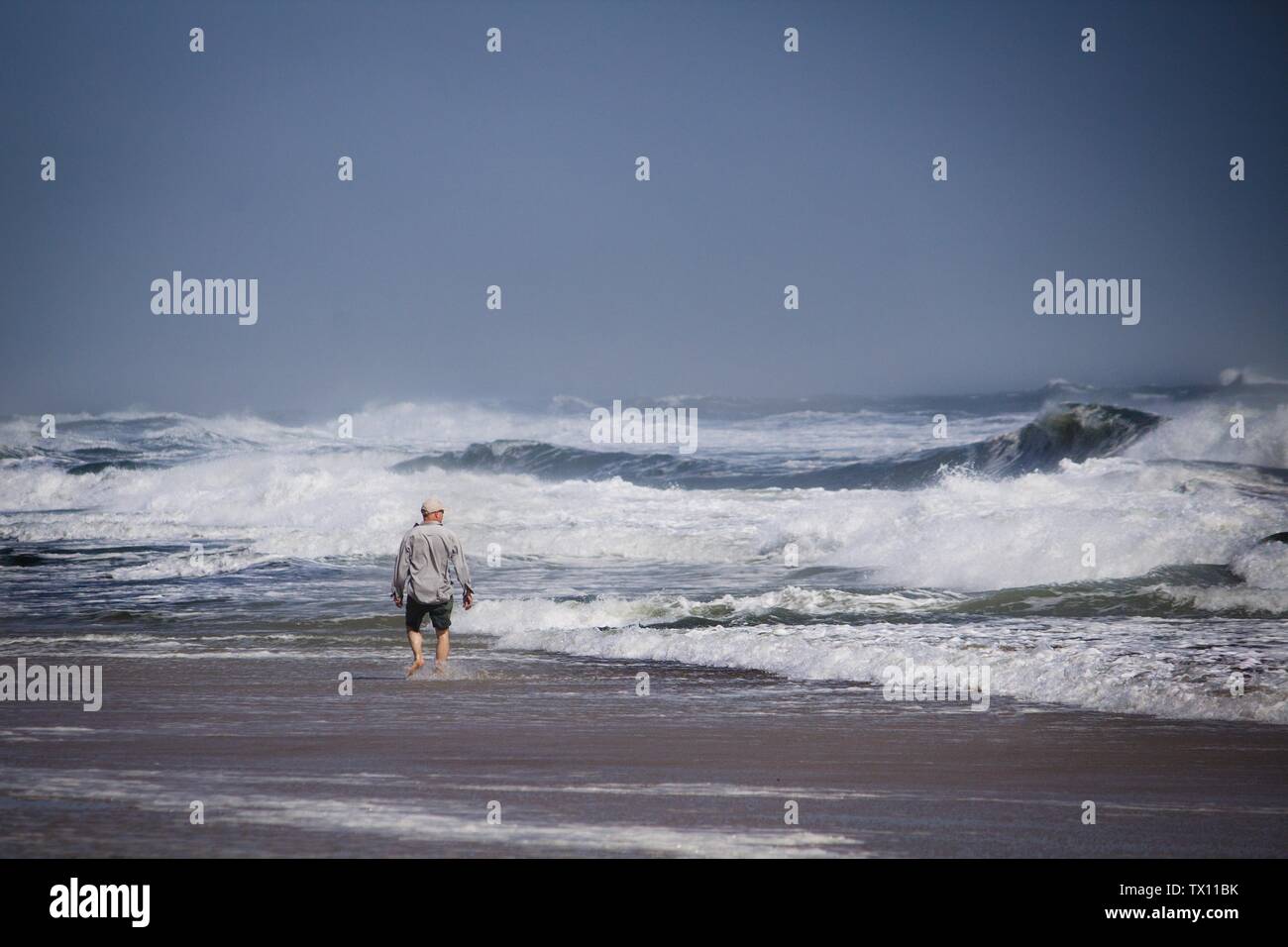 Male walking on the coast of the sea with amazing waves and clear blue ...