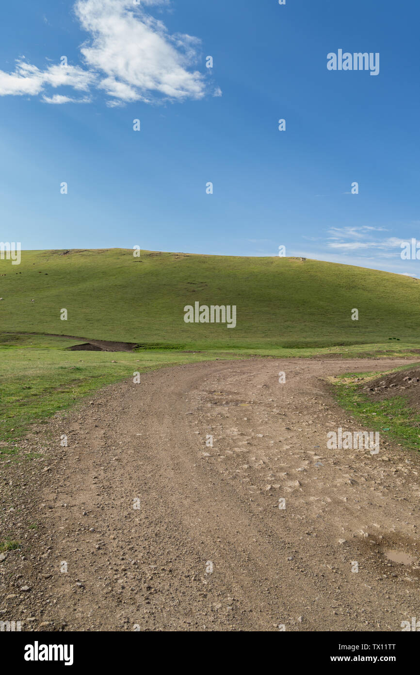 Blue sky and white clouds under hillside prairie sand and gravel ground ...