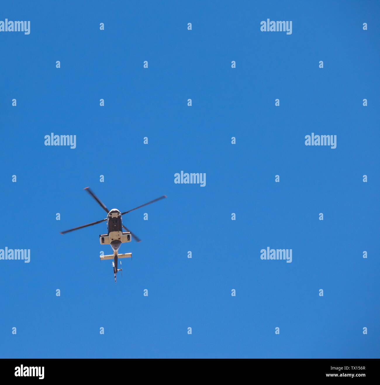 A helicopter in flight isolated in a clear blue sky image with copy ...