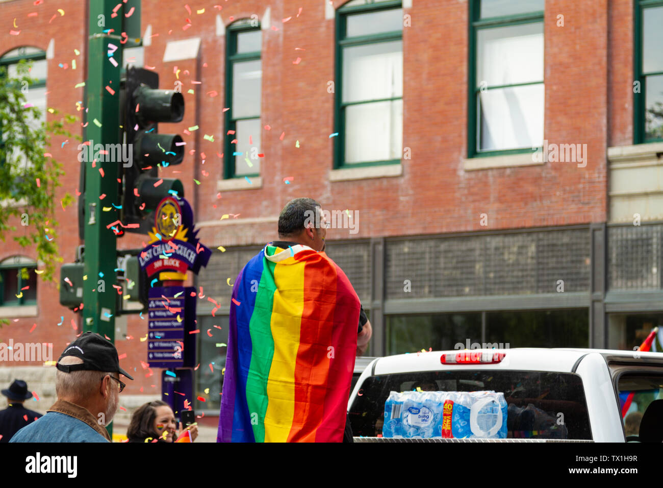 Man with a Rainbow flag draped over his shoulders and rainbow colored ...