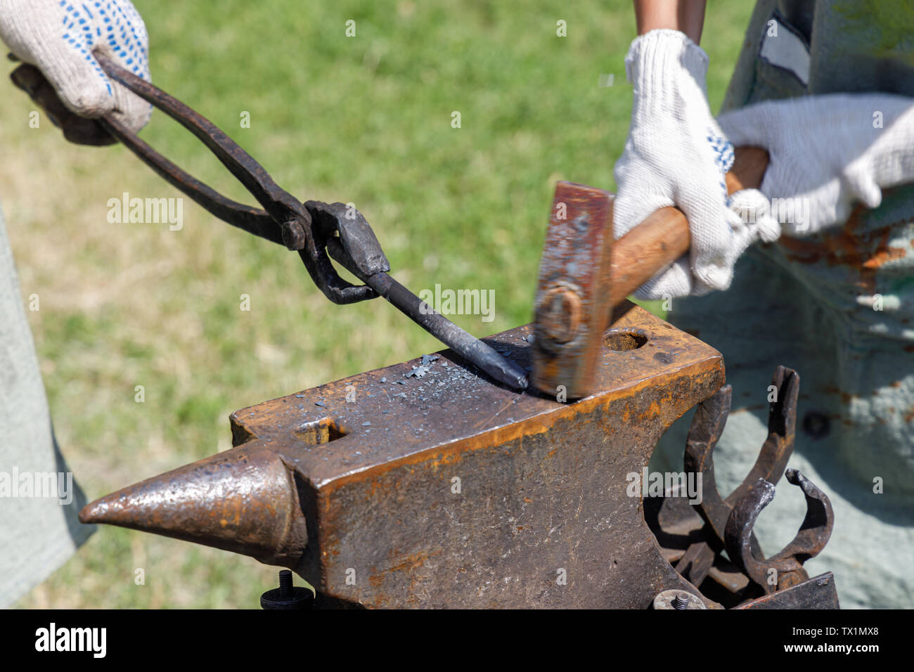 Blacksmith hammering on a metal billet lying on the anvil Stock Photo ...